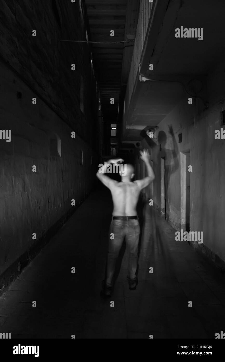 A Disturbed Inmate walks along a dark Asylum Corridor Stock Photo - Alamy