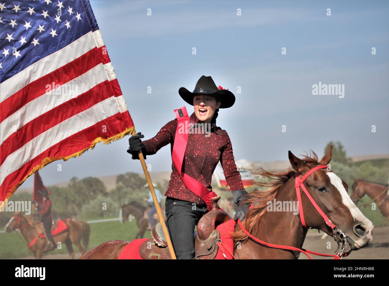 Pretty young woman flag carrier at a local farm rodeo with happy smile ...