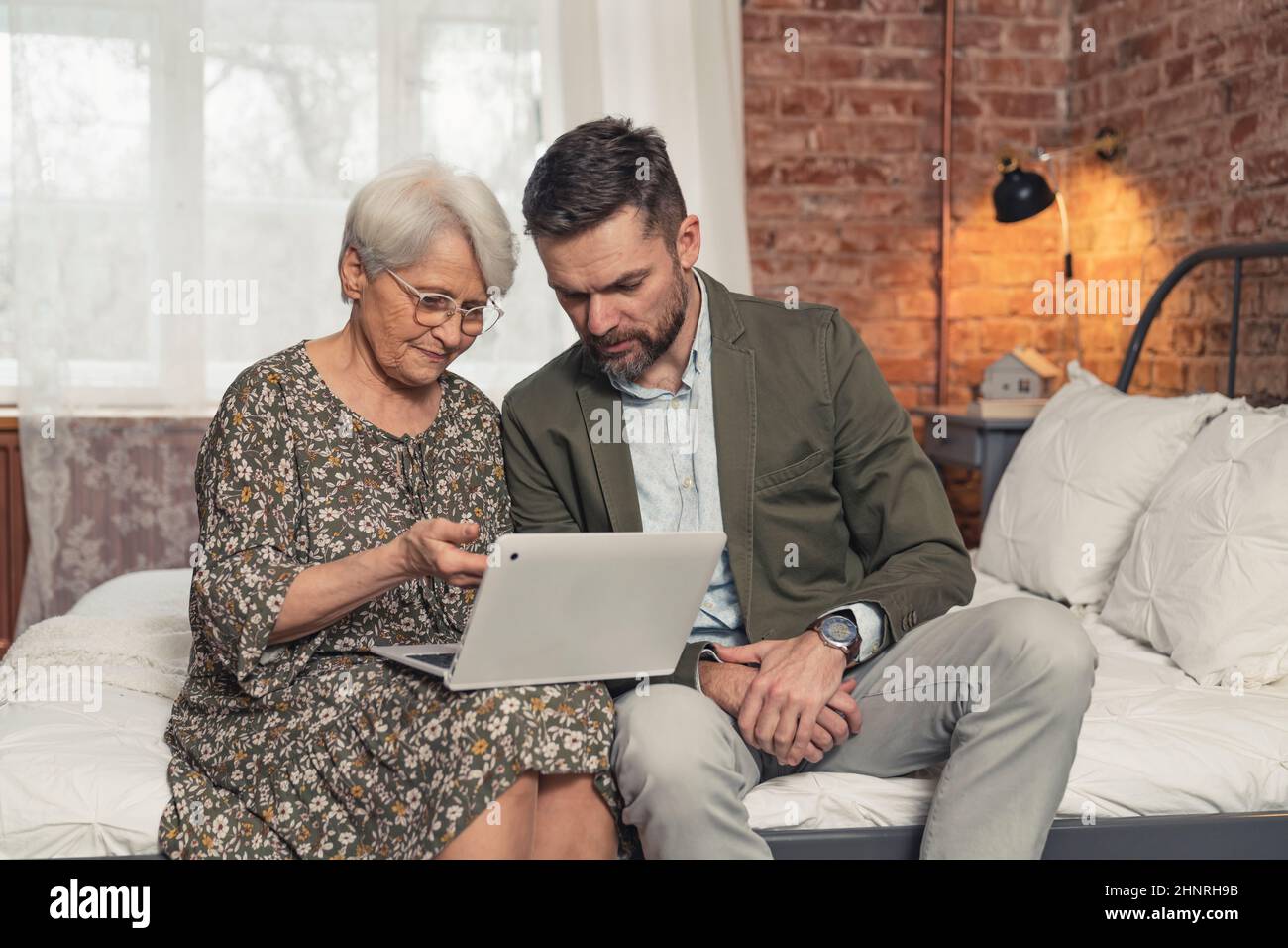 modern retired mother in her 70s showing her middle-aged son something ...