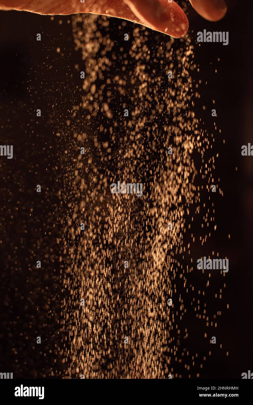 flying flour from hands on black background Stock Photo - Alamy
