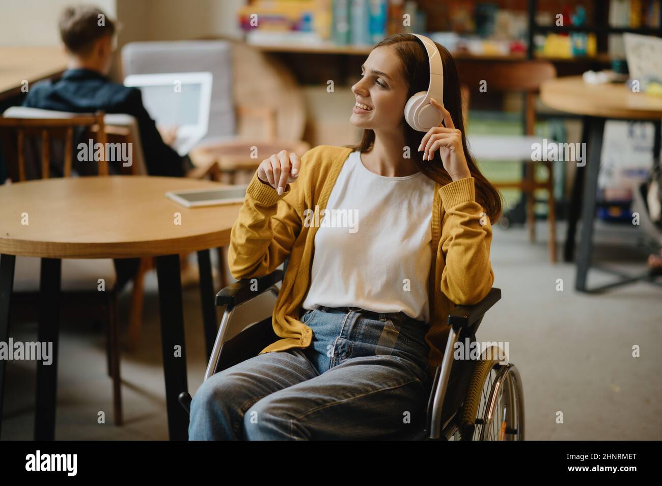 Disabled female student in wheelchair listen to music in headphones ...