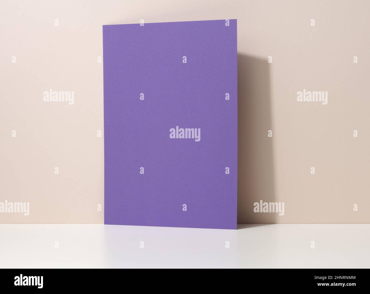 blank purple cardboard sheet of paper with shadow on white table ...