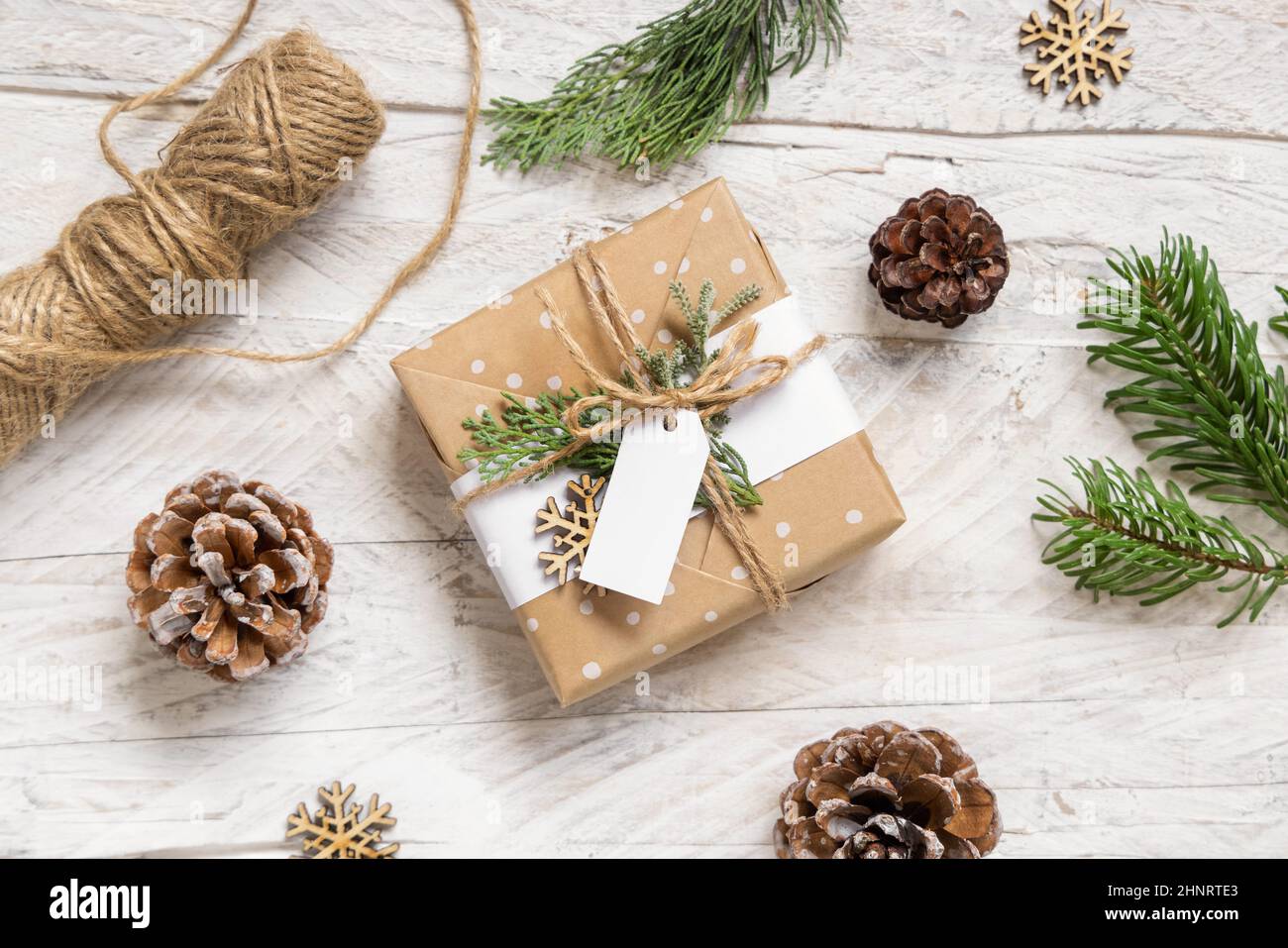 Christmas wrapped present with paper gift tag on a white table with fir ...