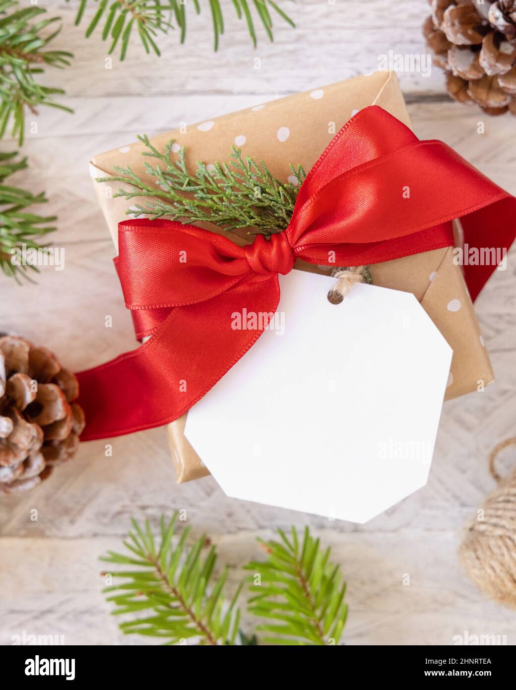 Christmas wrapped present with paper gift tag on a white table with fir ...
