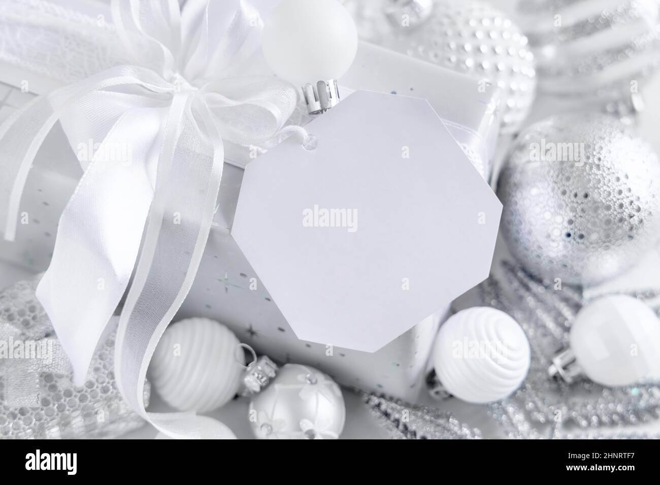 Wrapped present with a white bow and paper gift tag on a white table ...