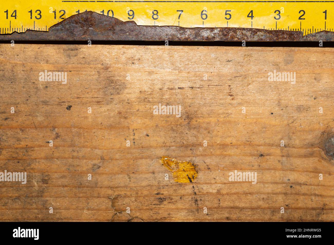 Old rusty yellow ruler with black numbers on a working wooden table ...