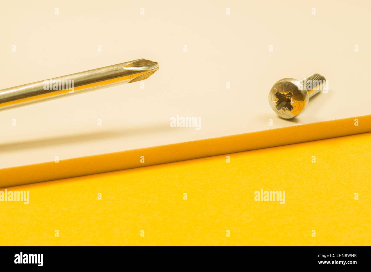 Steel screw on a yellow background. working tools Stock Photo - Alamy