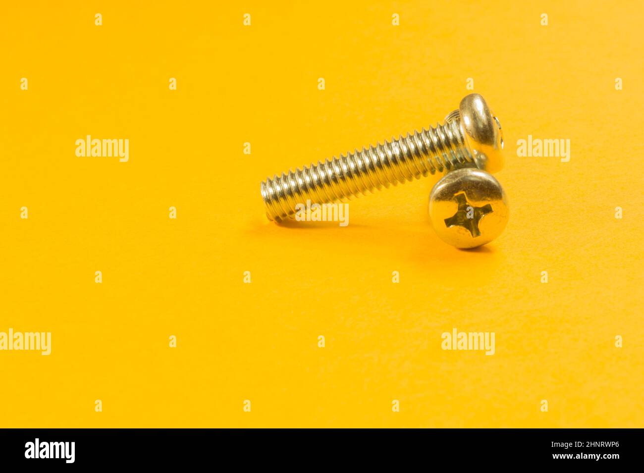 Steel screw on a yellow background. working tools Stock Photo - Alamy