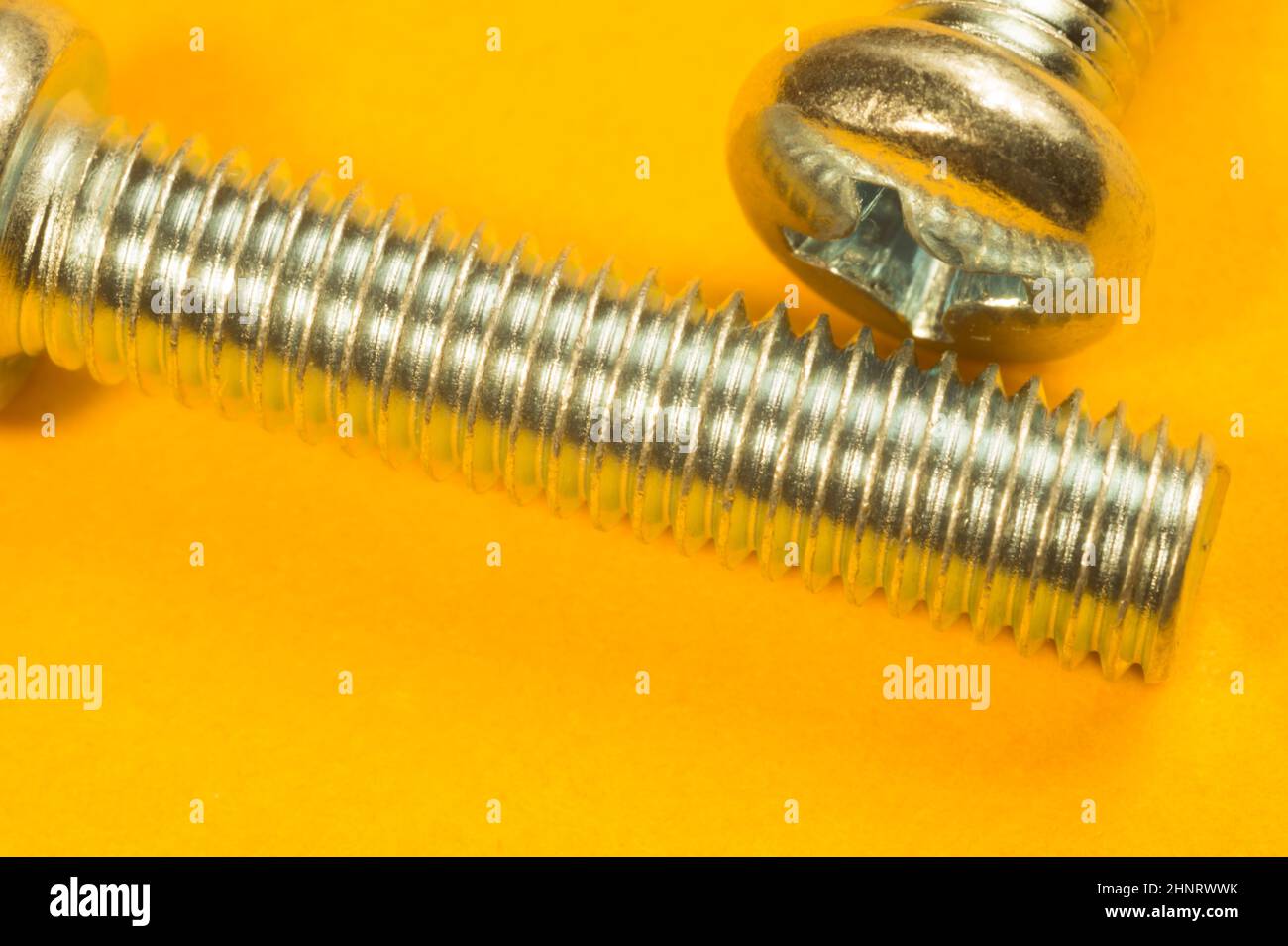 Steel screw on a yellow background. working tools Stock Photo - Alamy