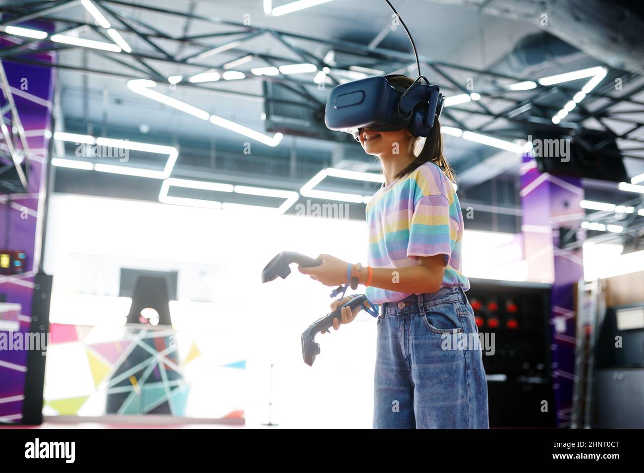 Little girl in vr glasses holds joysticks in her hands. Kid playing 3d ...