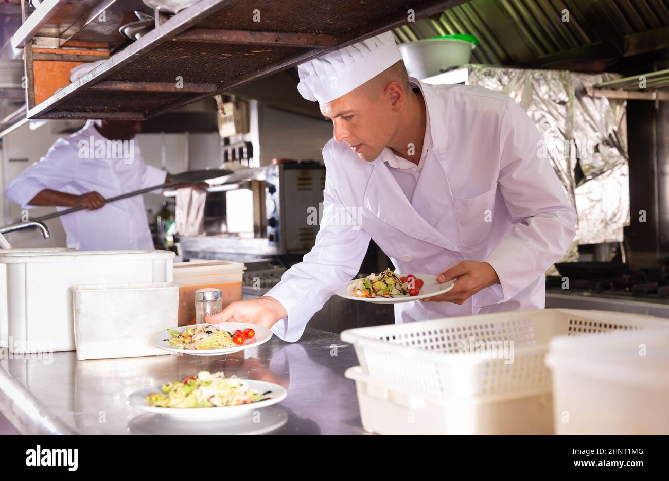 Professional cook working with assistants in restaurant kitchen Stock ...