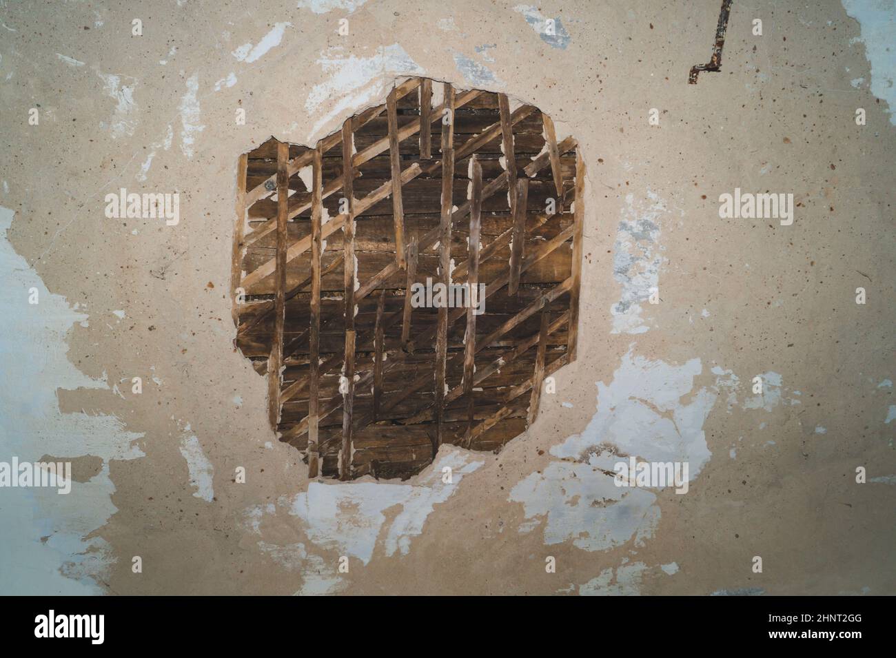 Dilapidated ceiling of an old house. damaged wall with a hole with ...