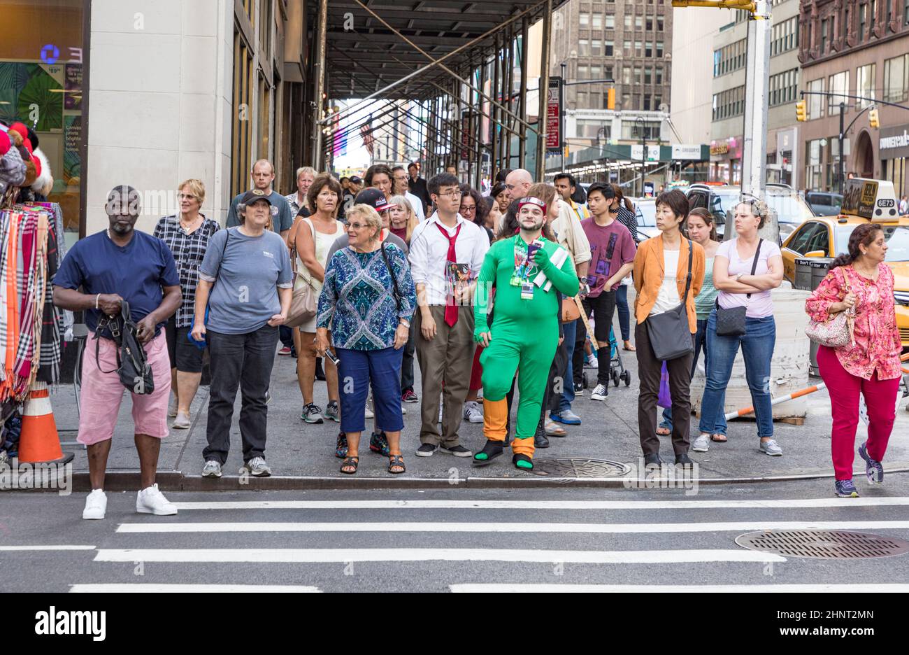 people waiting at a pedestrian crossing for green sign to cross the ...