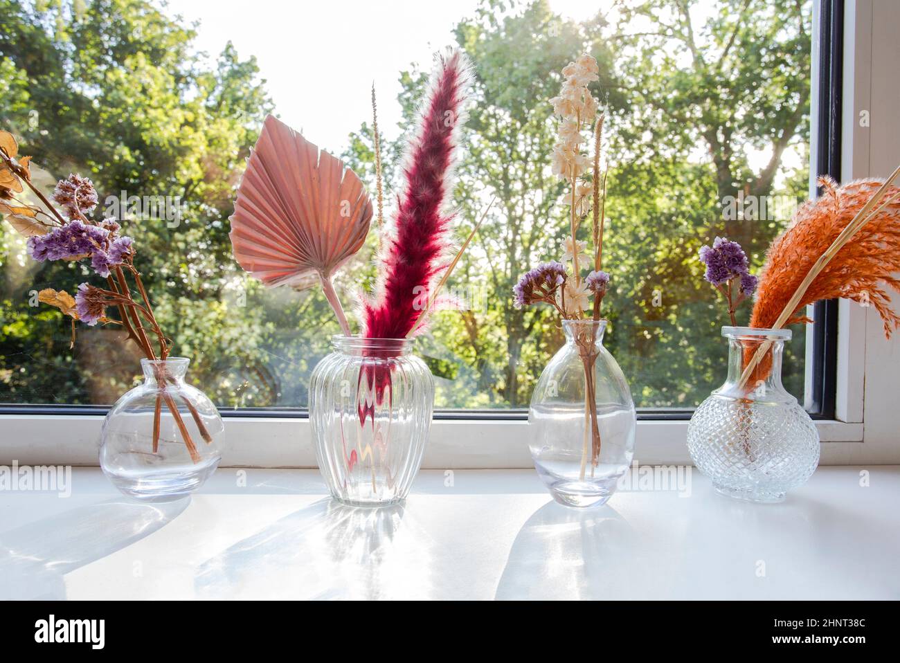 decorative vases and flowers with interior decor concept on window sill ...