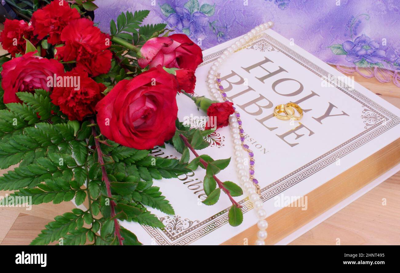 Roses and Wedding Rings and Jewelry on Holy Bible Stock Photo - Alamy