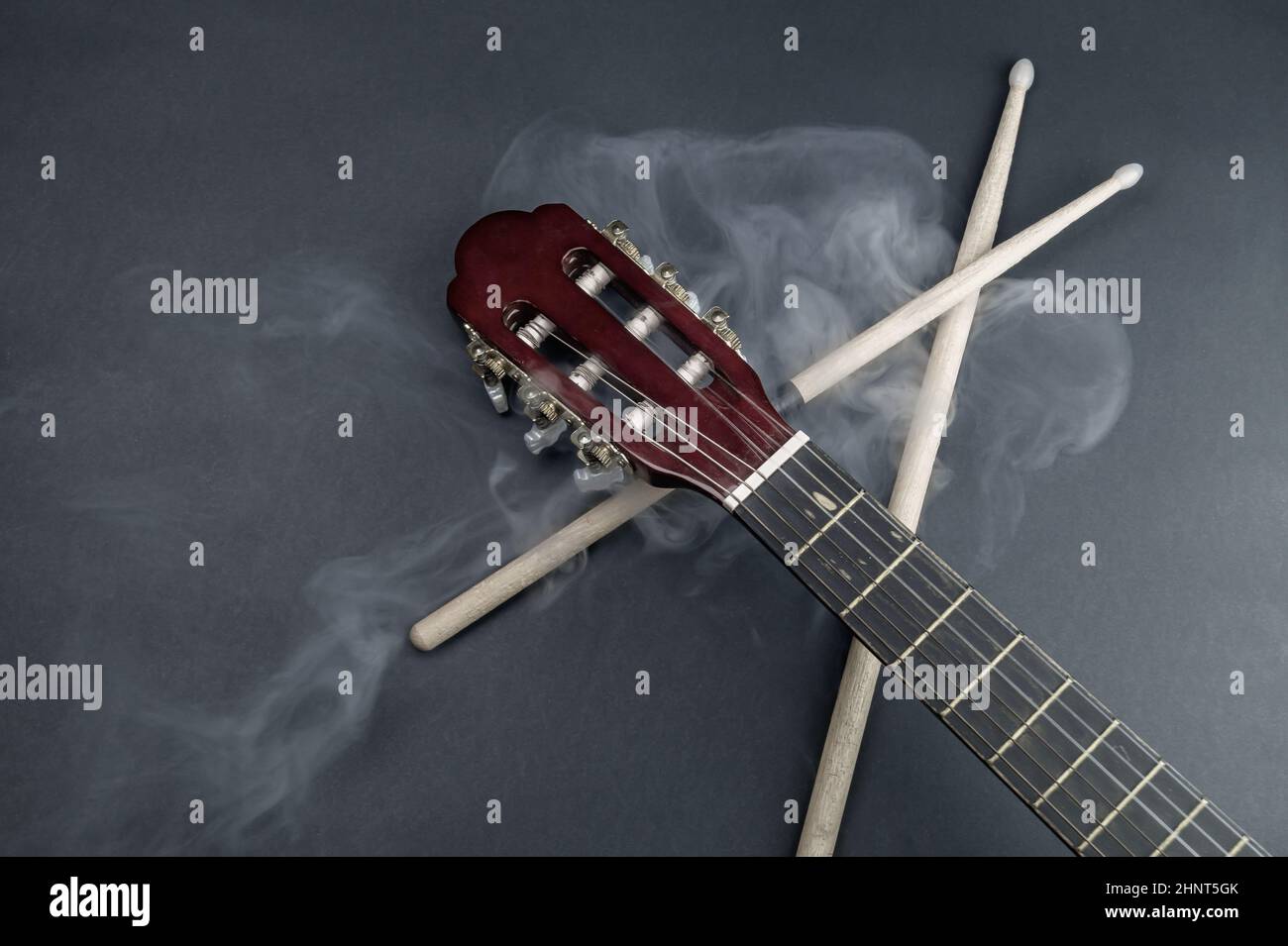 Drumsticks and guitar fretboard in smoke. acoustic musical instrument ...