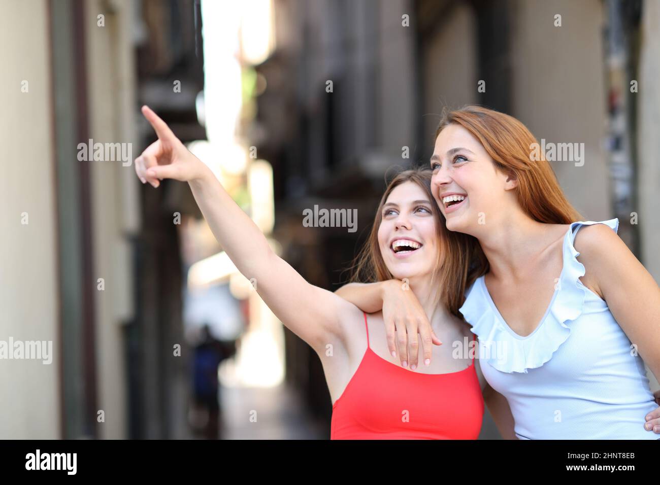 Two happy friends laughing together pointing up in the street Stock ...