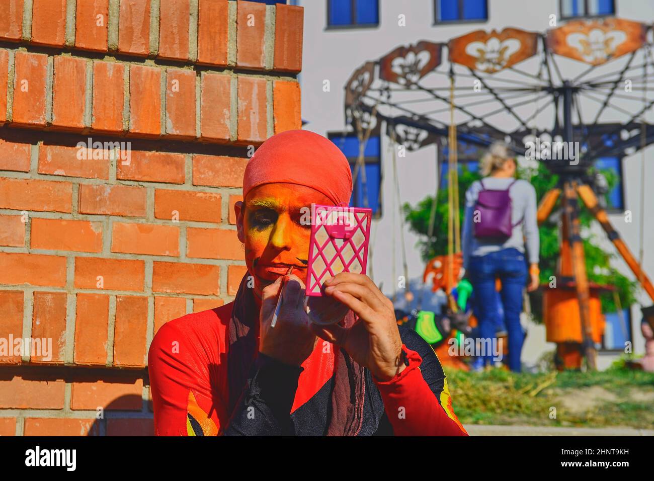 Street performer putting on his face make-up. Street performers can ...