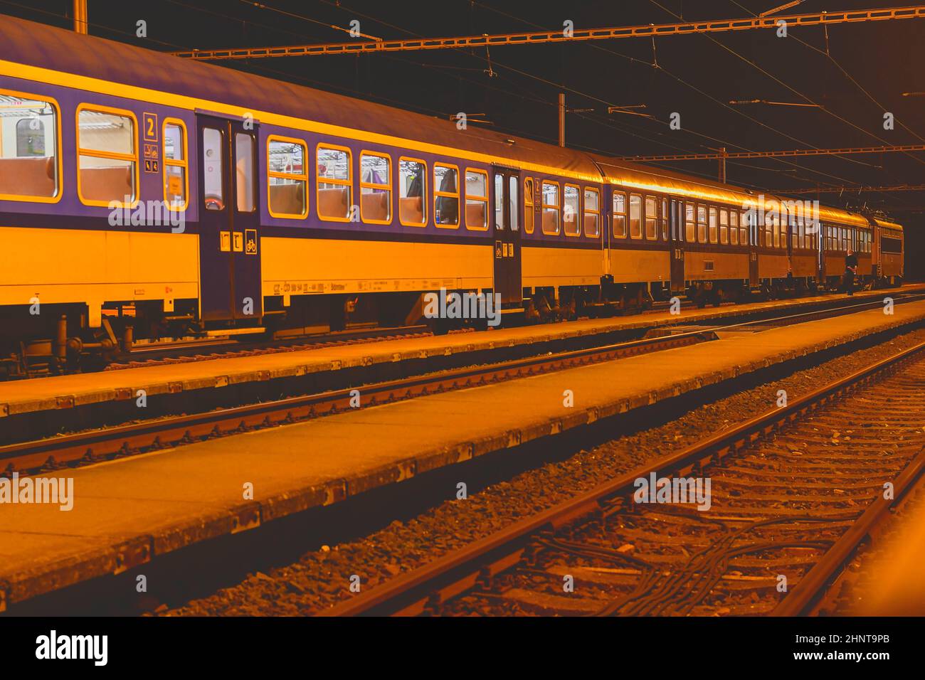 White and blue train standing at a small roofless train station at ...