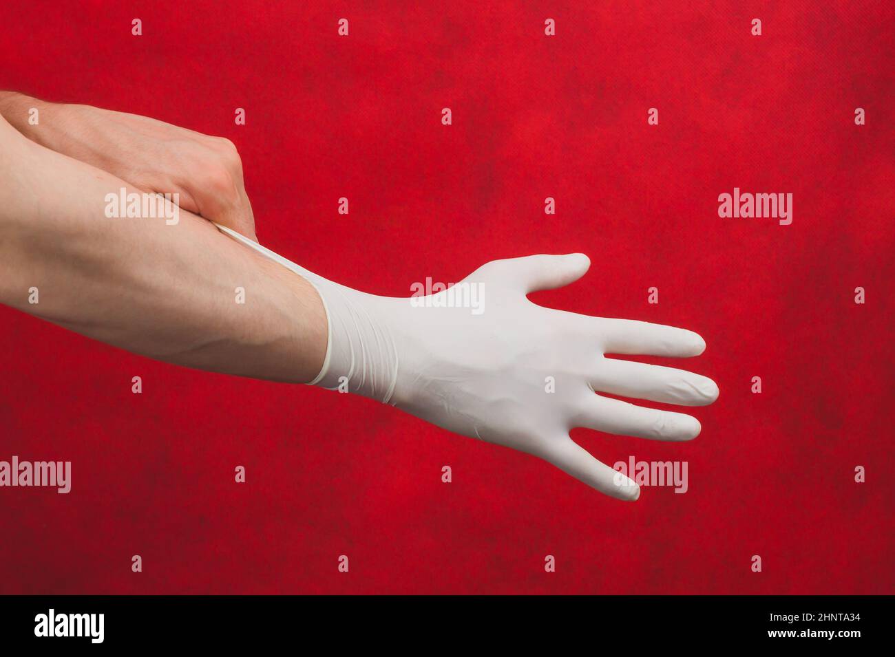 Hand in medical glove. person puts on surgical gloves on a red ...