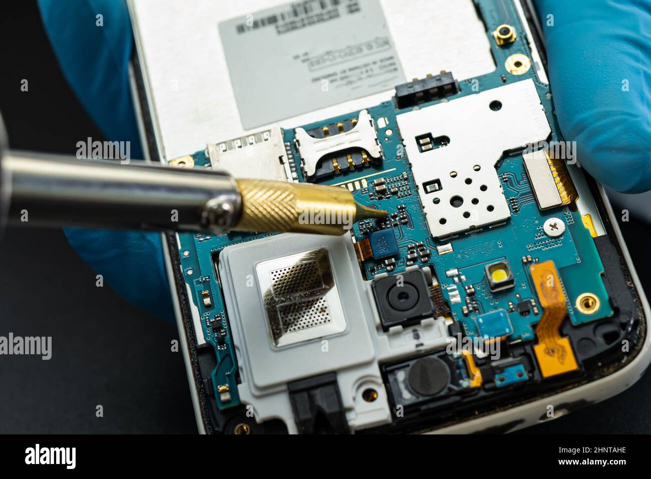 Technician repairing inside of mobile phone by soldering iron ...
