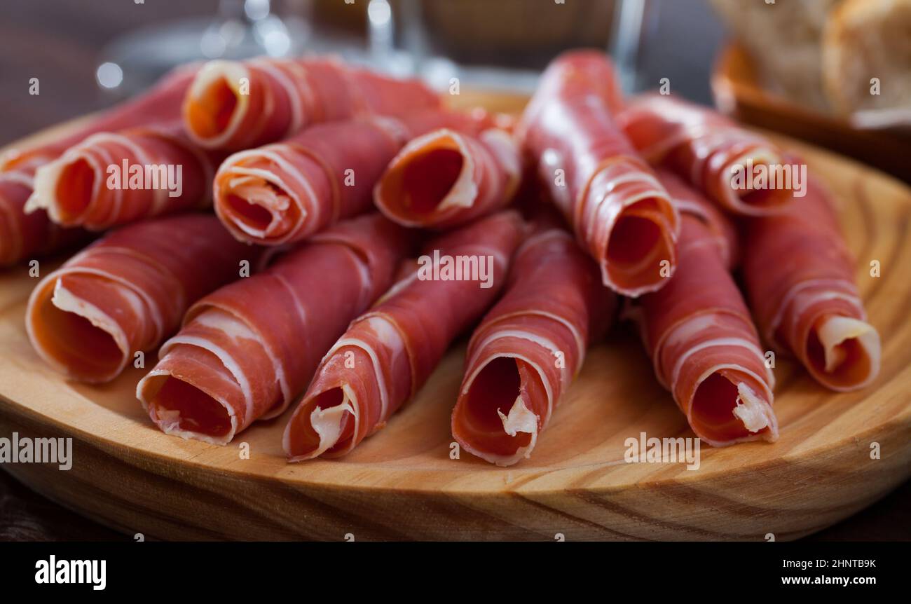 Spanish tasty meal rolls of prosciutto di parma at wooden desk Stock ...