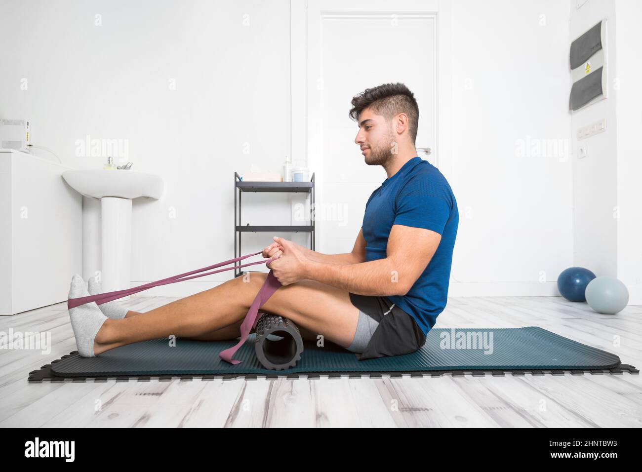 Young man Using Yoga Belt While Doing Exercise On Fitness Mat At ...