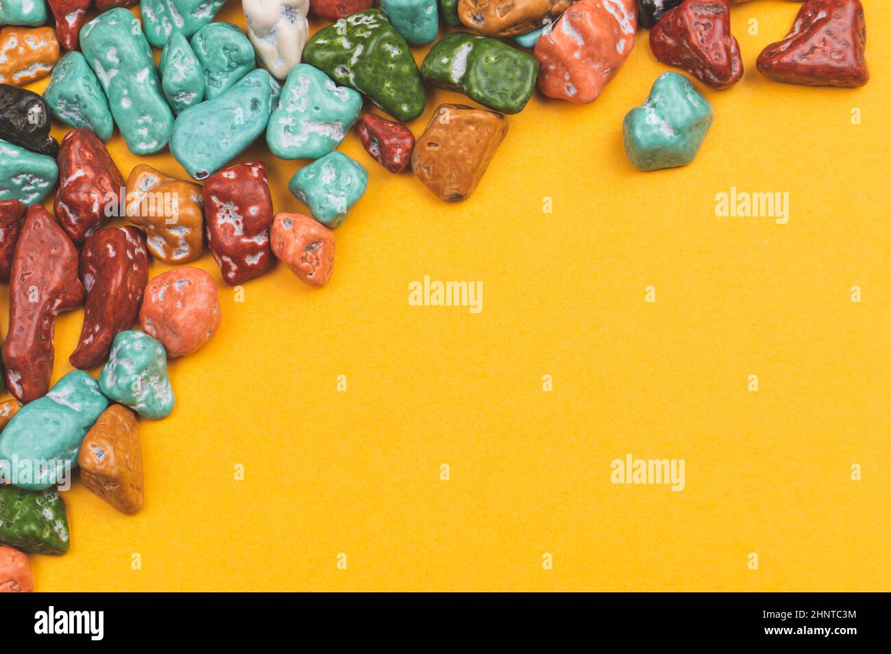 Candy pebbles on a yellow background. sweets in the form of colored ...