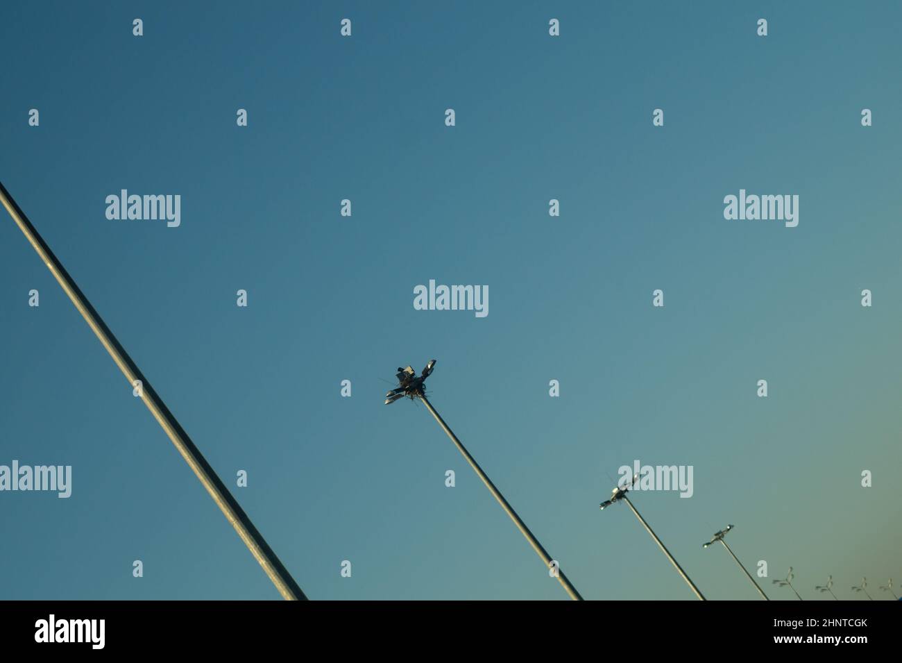 Street lamp posts standing in order on a highway with clear sky ...