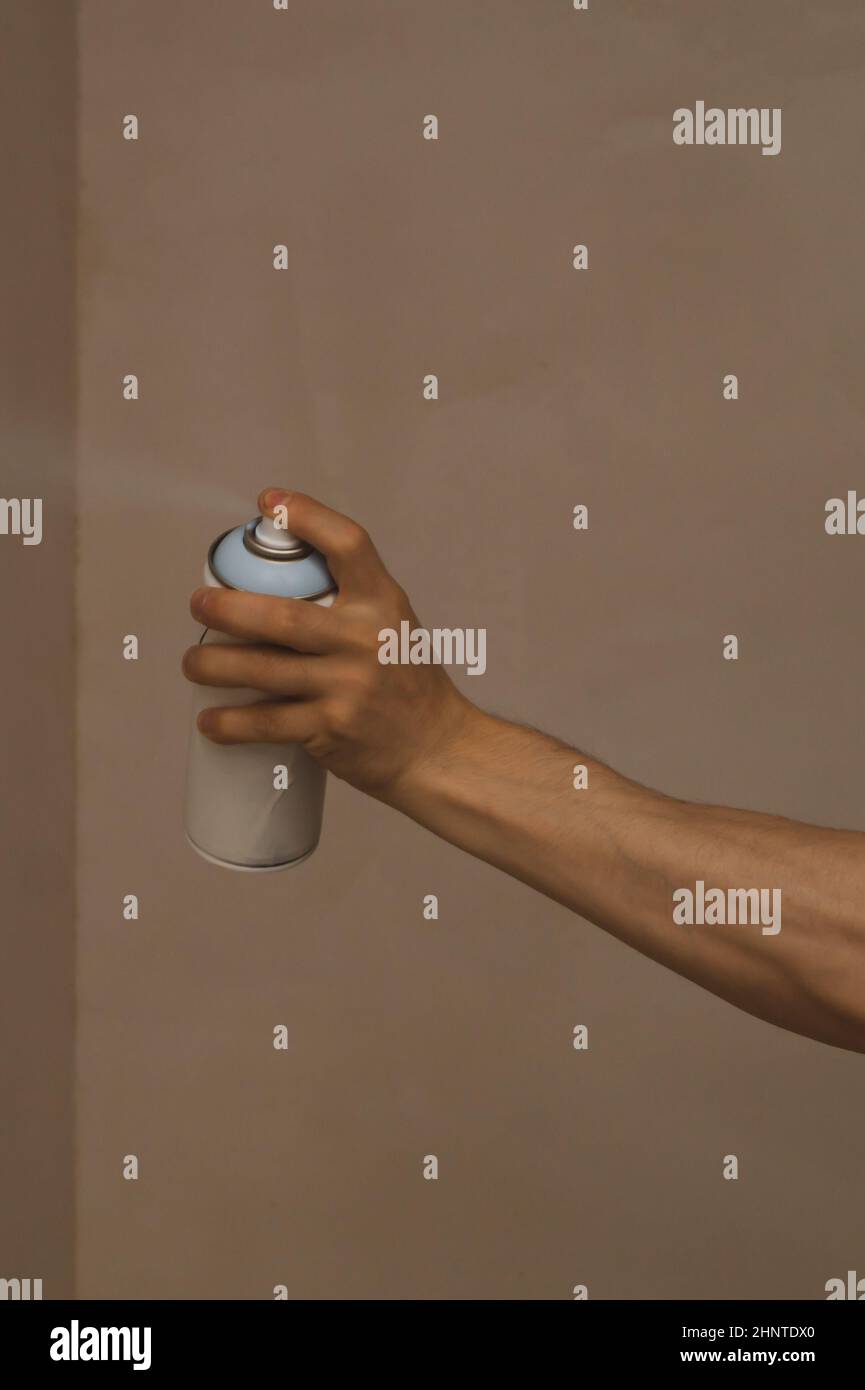 Spray can in the hand. spraying paint on the wall. painting process ...