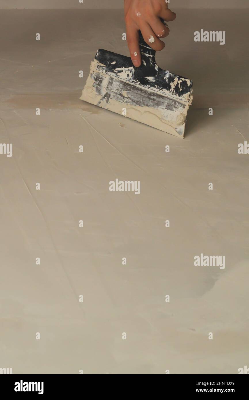 Hand holds construction spatula with putty. trowel with spackling ...