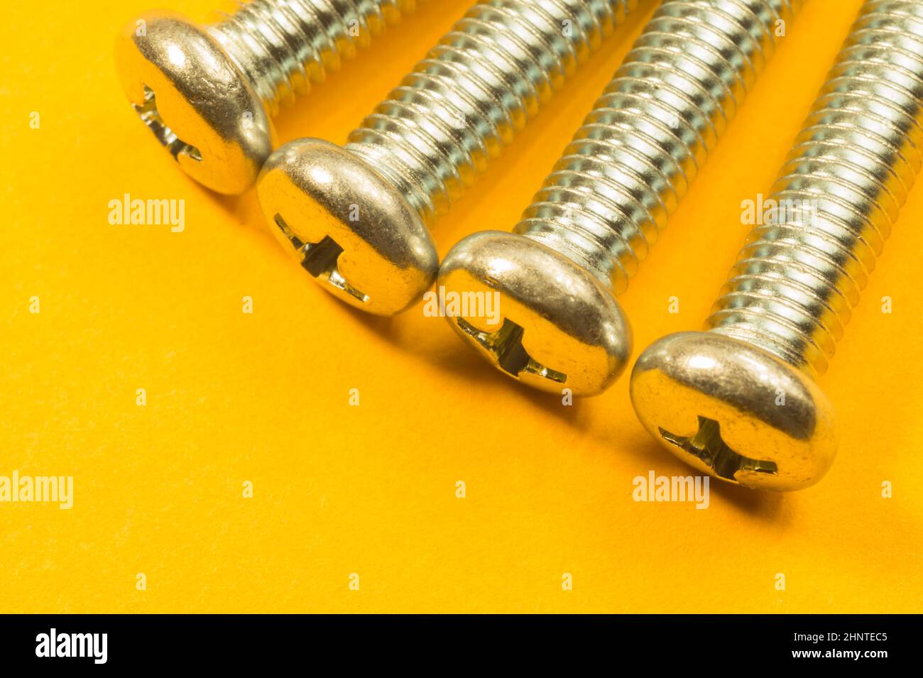 Steel screw on a yellow background. working tools Stock Photo - Alamy