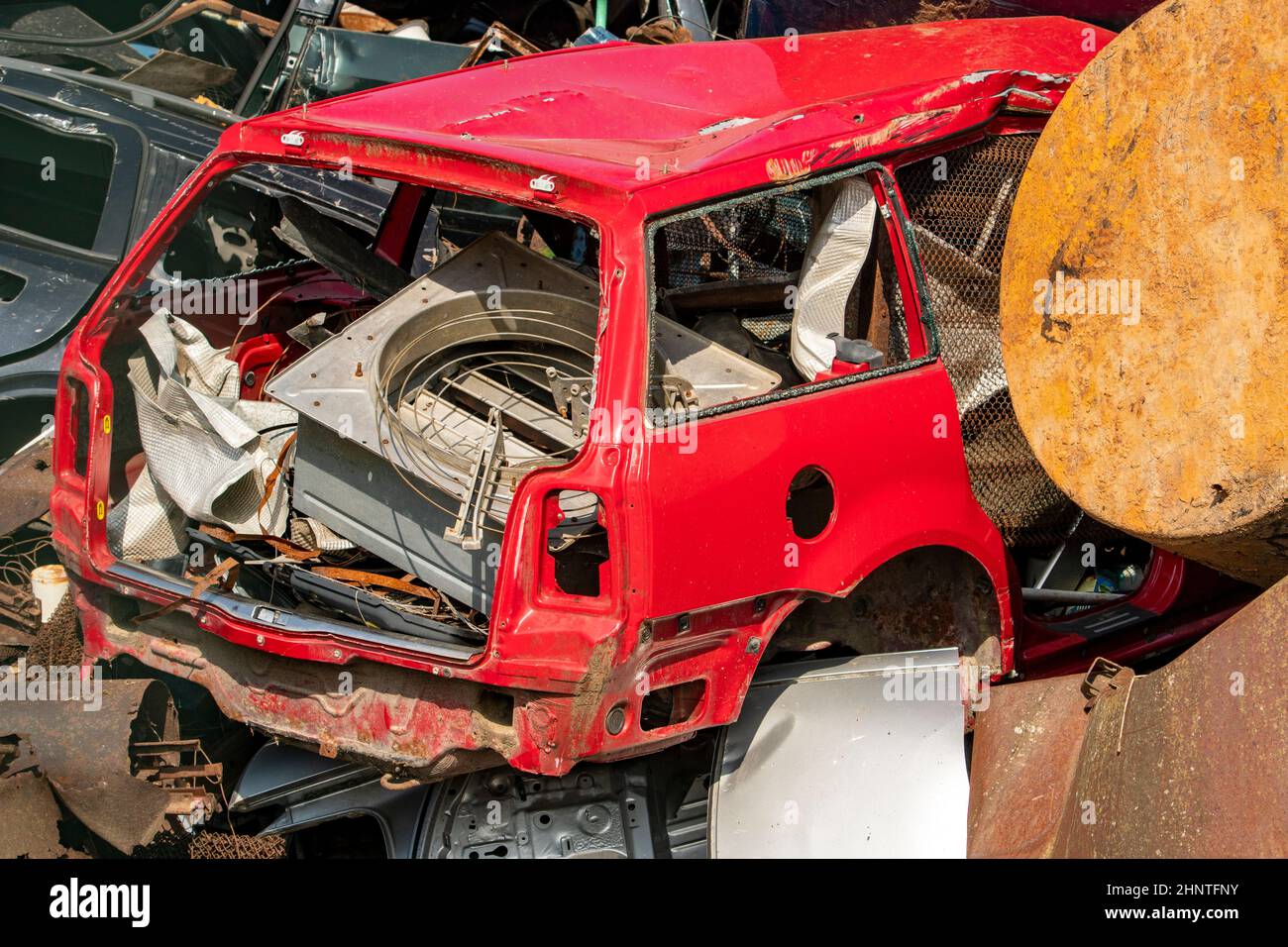 Damaged red car waiting in a wreck yard to be recycled Stock Photo - Alamy
