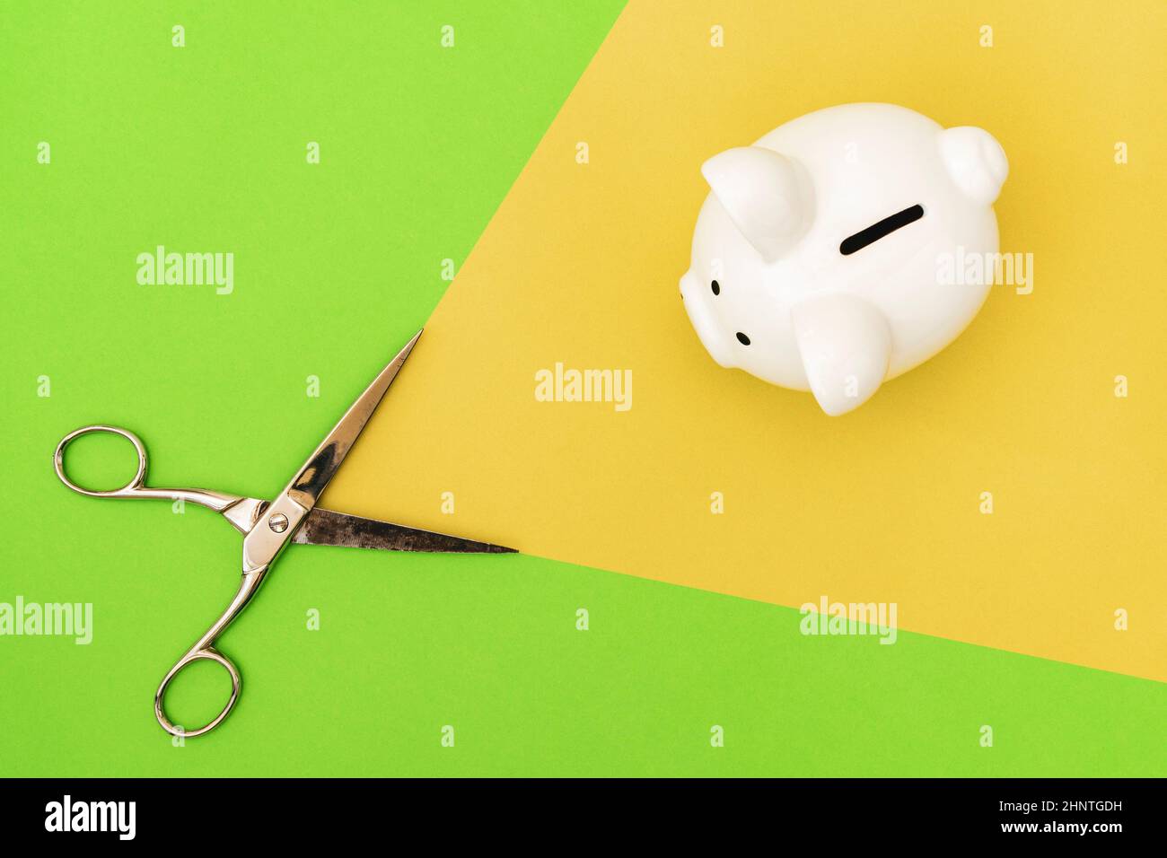 Cut savings concept. Piggy bank and scissors on the colored background ...