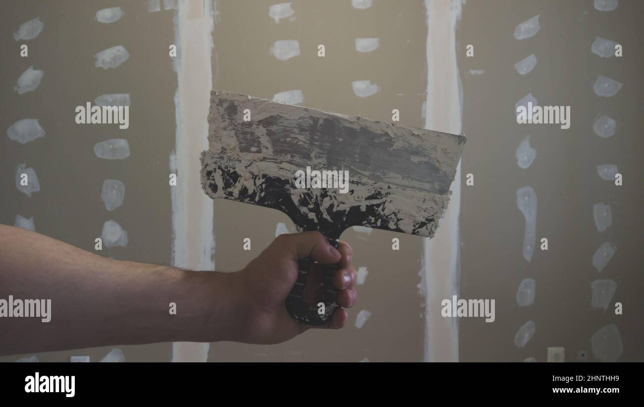 Hand holds construction spatula with putty. trowel with spackling ...