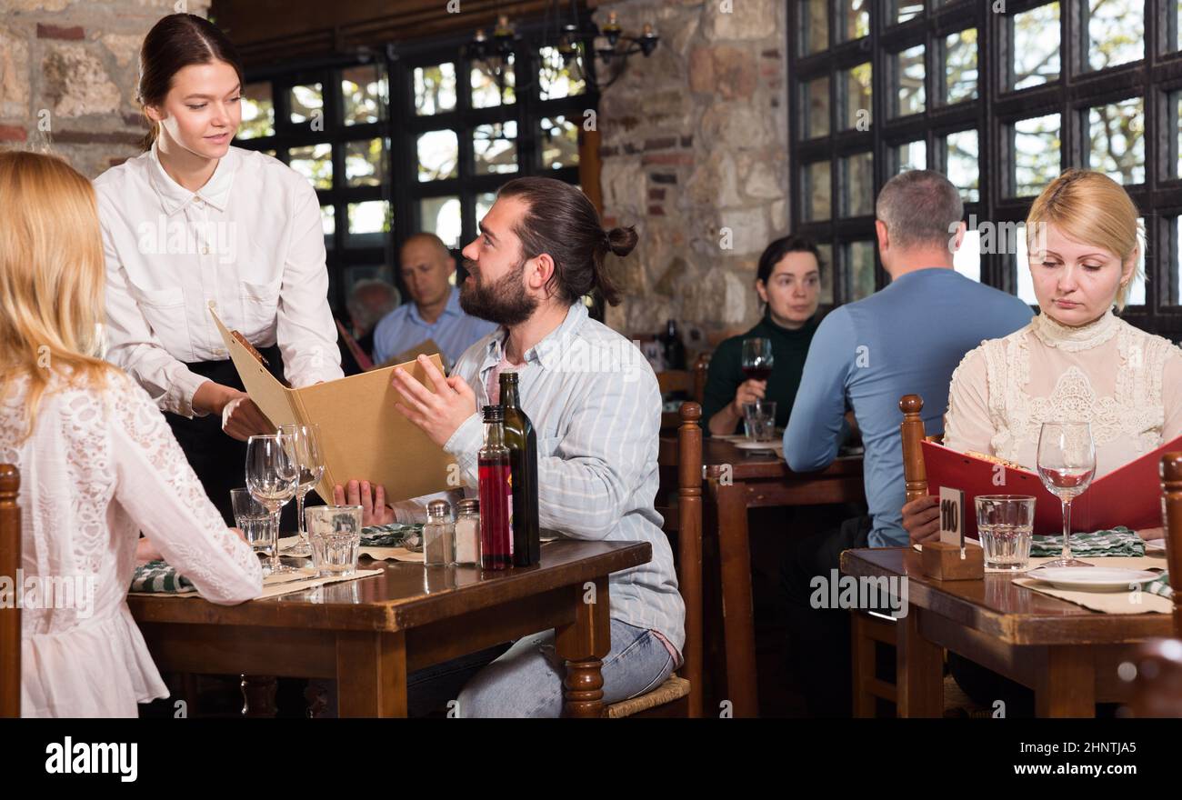 Female owner of restaurant helping guests with menu Stock Photo - Alamy