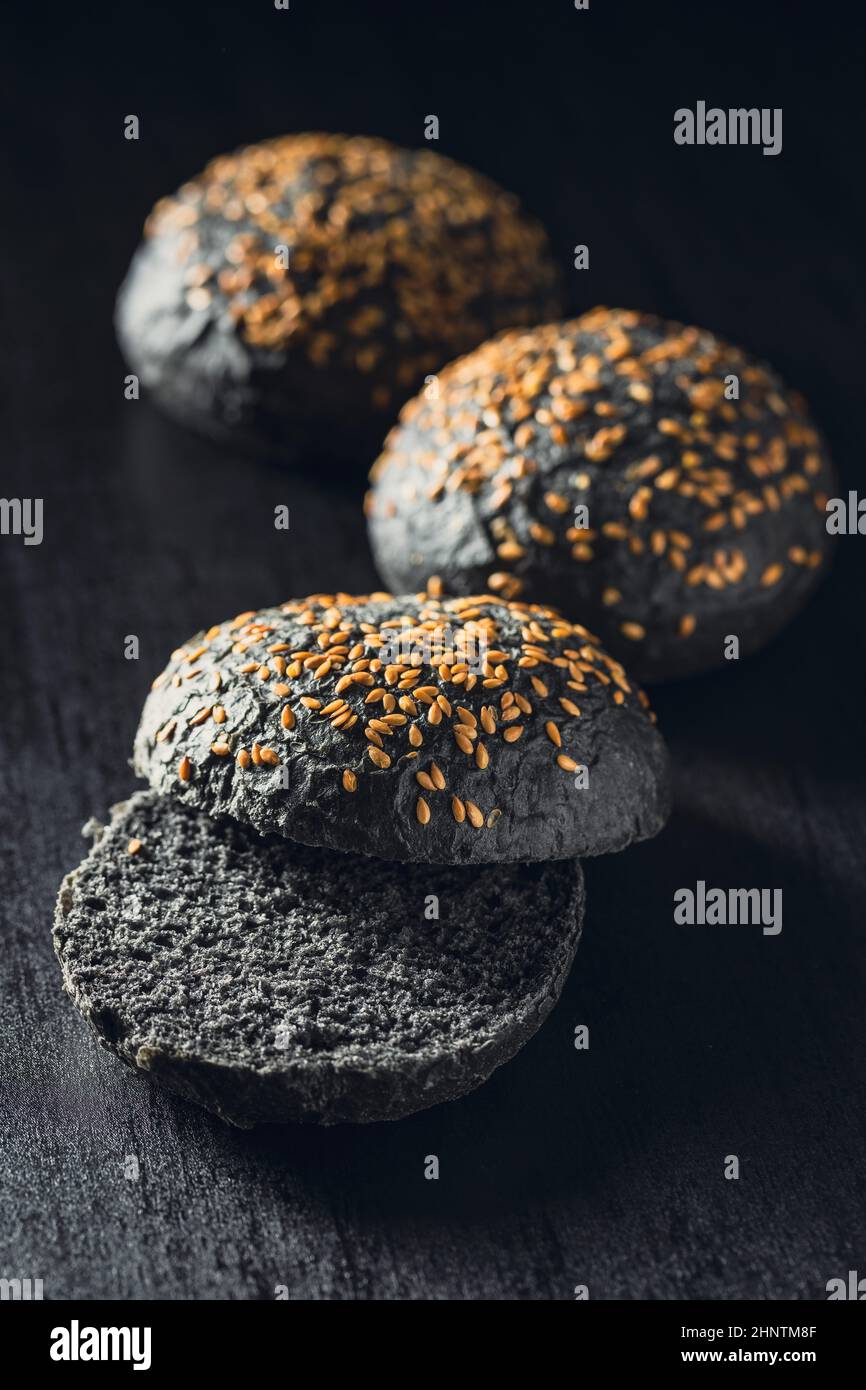 Black bun. Dark pastry with sesame seeds on black table Stock Photo - Alamy