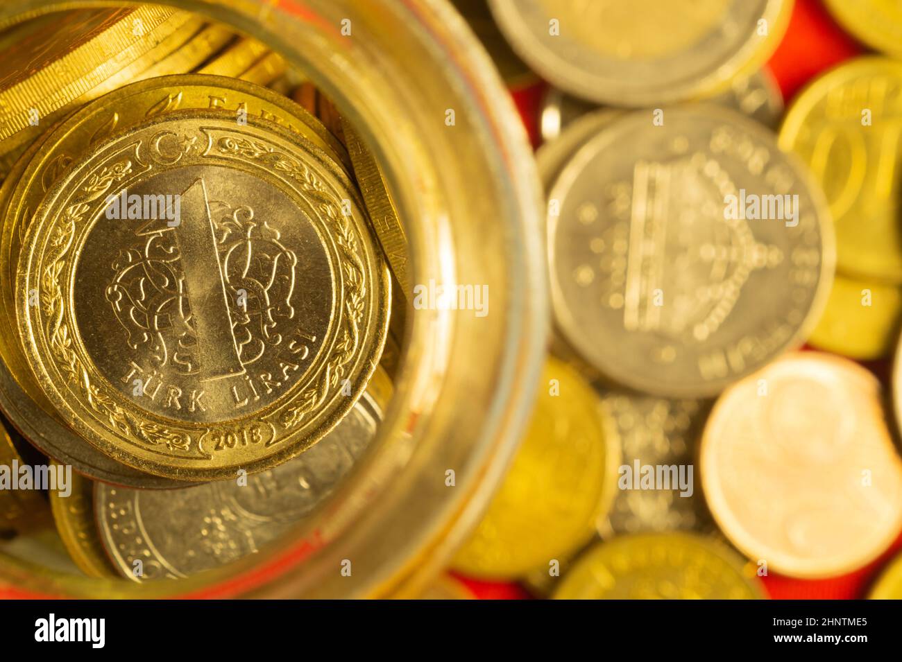 Coins of different countries in a glass jar. a lot of metal coins of ...