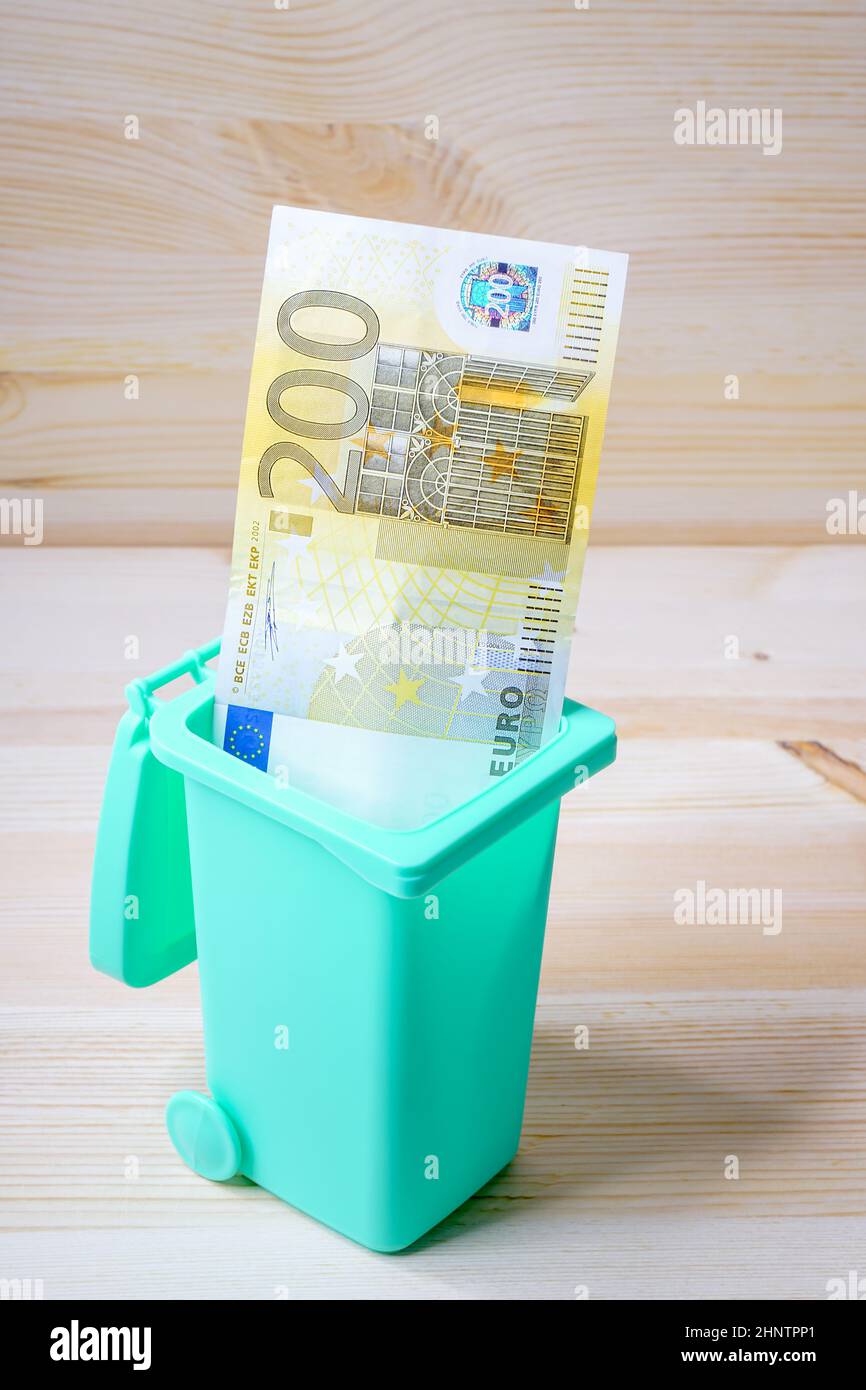 Euro banknote in a garbage can as a symbol for garbage fees, waste of ...