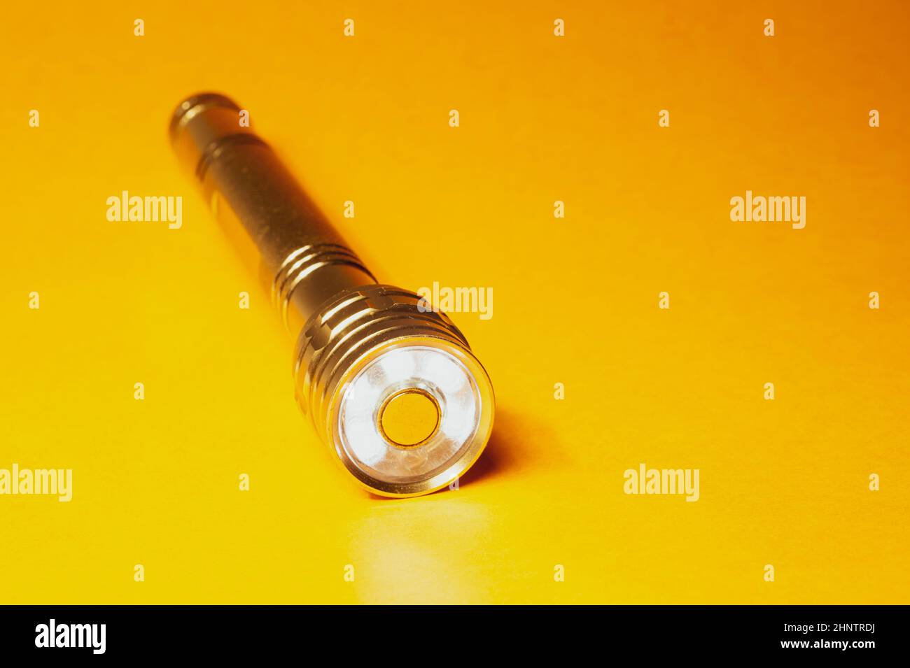 Metal flashlight on a yellow background Stock Photo - Alamy