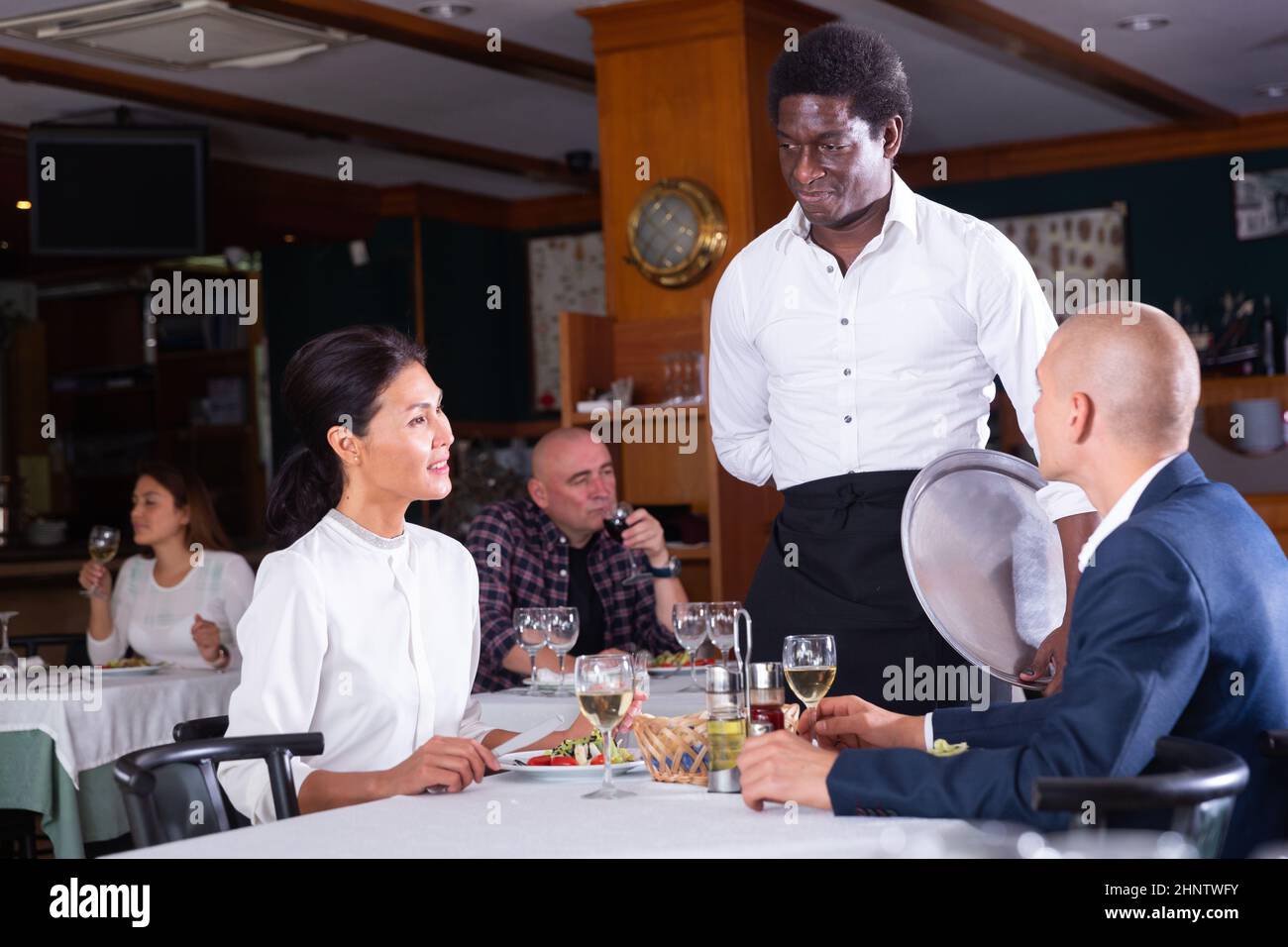 Friendly african american waiter talking with restaurant guests Stock ...