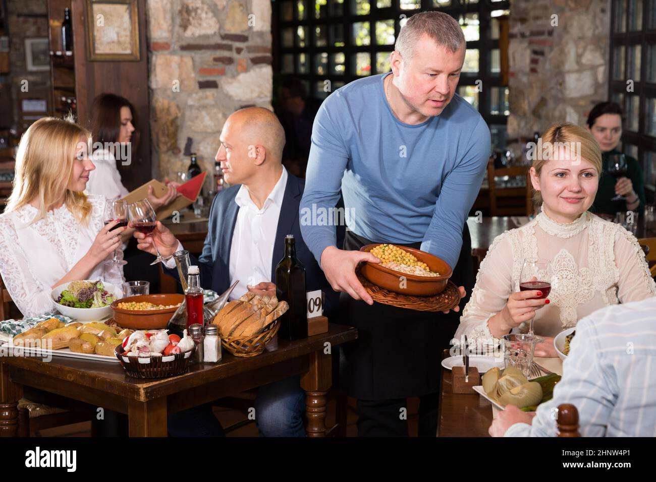 Rustic restaurant owner serving guests Stock Photo - Alamy