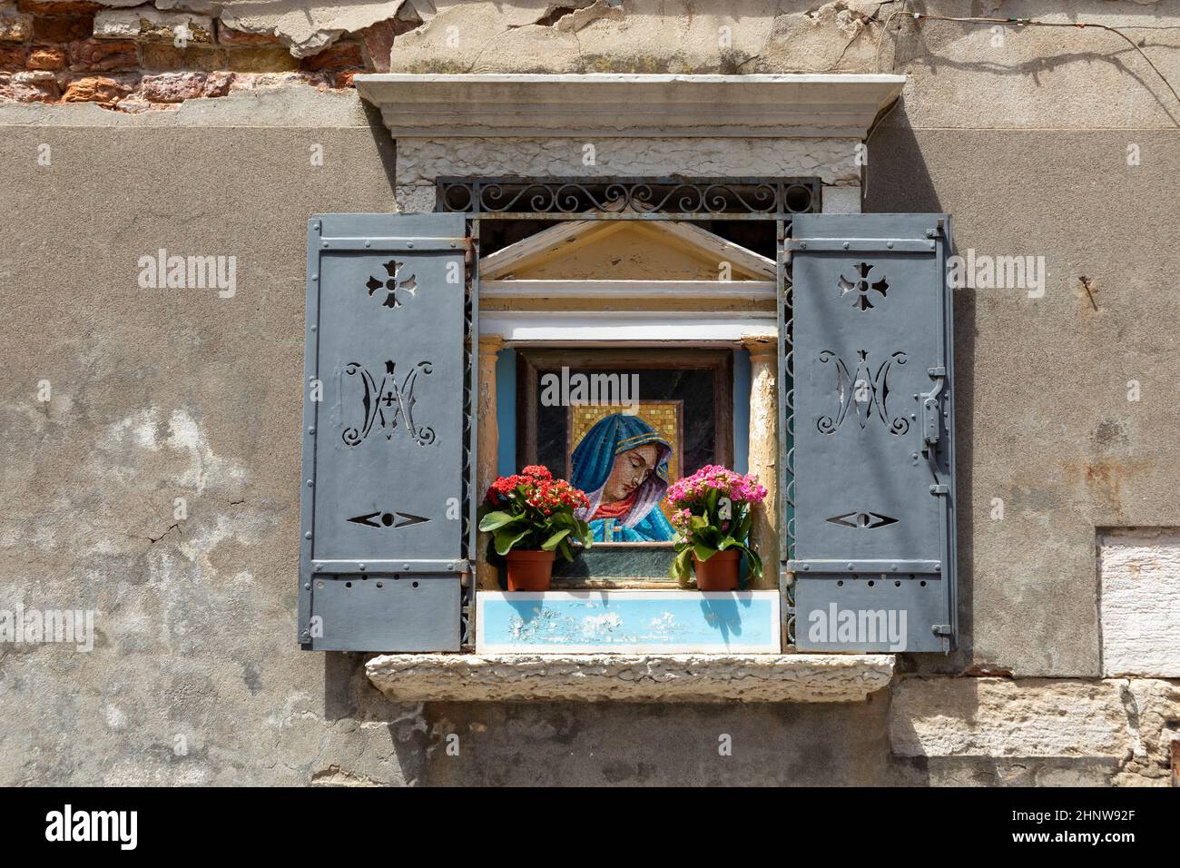 old open window with mosaic of virgen mary with flower pot and historic ...