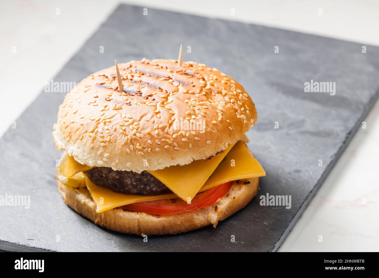 still life of cheeseburger on black plate Stock Photo - Alamy