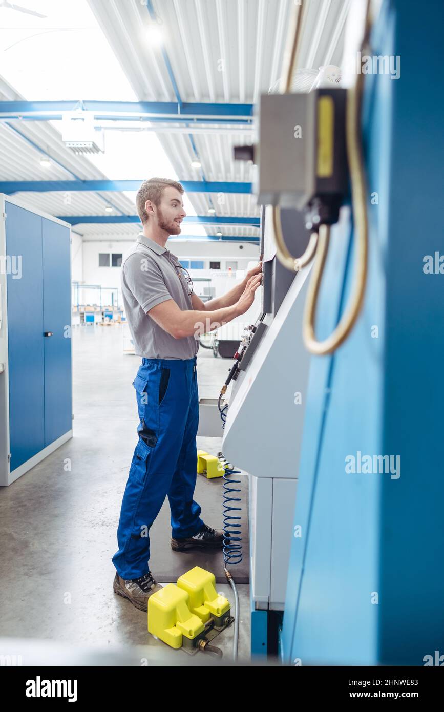 Manufacturing worker programming industrial CNC machine tool while entering work data Stock ...