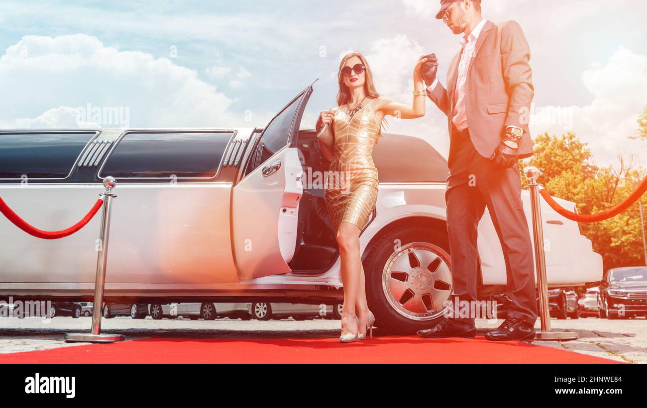 Driver helping VIP woman or star out of limo on red carpet to a ...