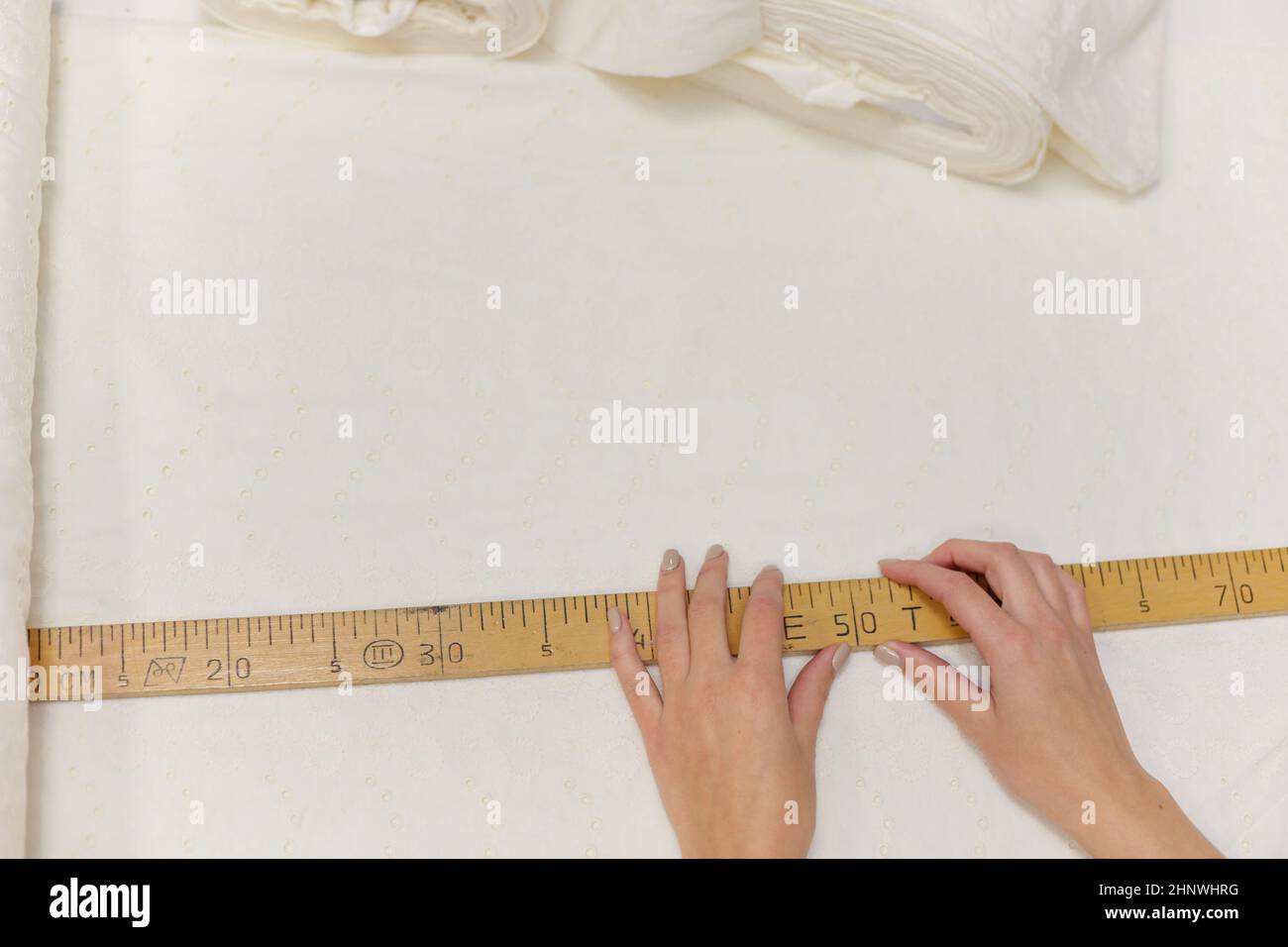Female hands using wooden tailor ruler to measure cotton fabric ...