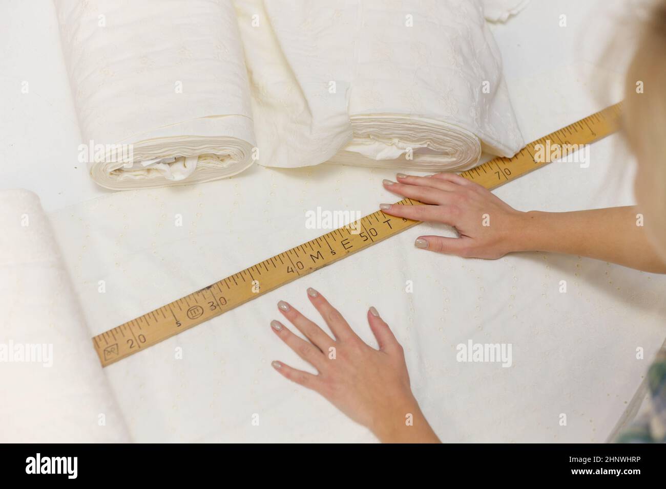 Female hands using wooden tailor ruler to measure cotton fabric ...