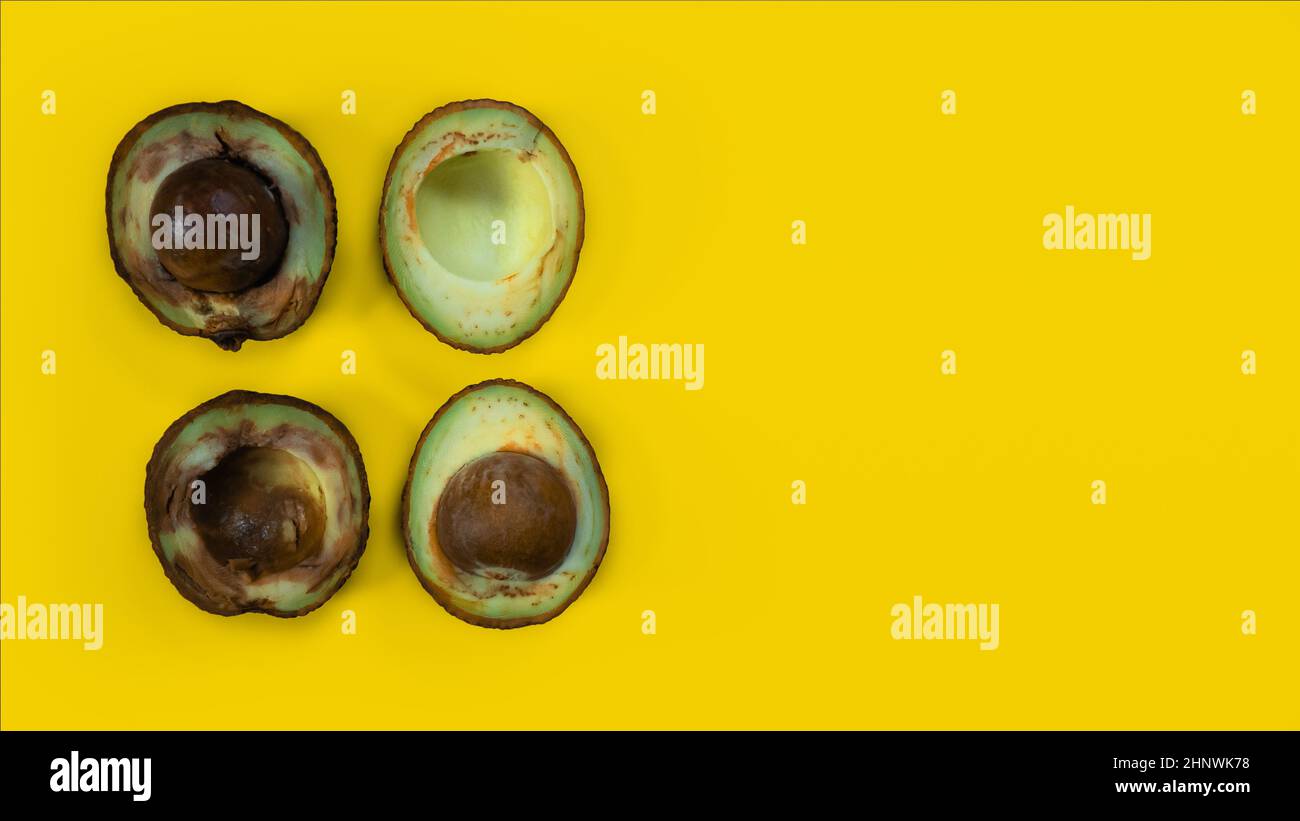 Two bad avocado. Ugly food on yellow background. Rotten tropical fruits ...