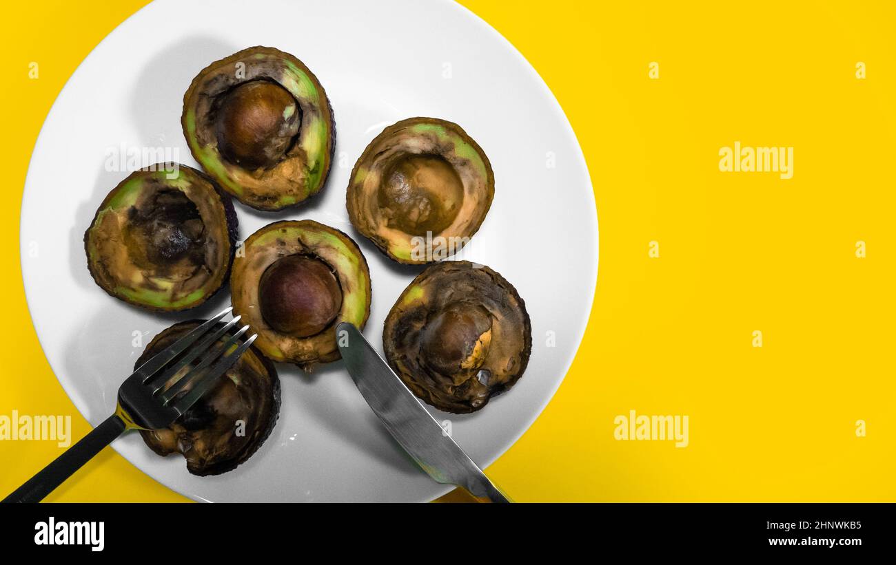 Bad Avocado halfs placed on plate with fork and knife Yellow background ...